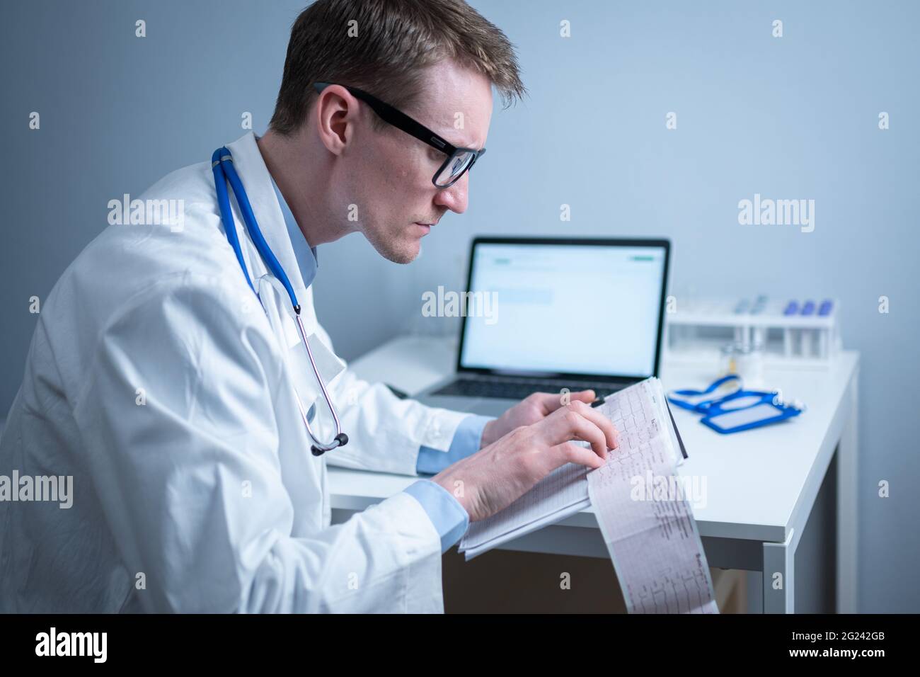 Cardiologist reading an ECG print-out. Doctor analyzing ...