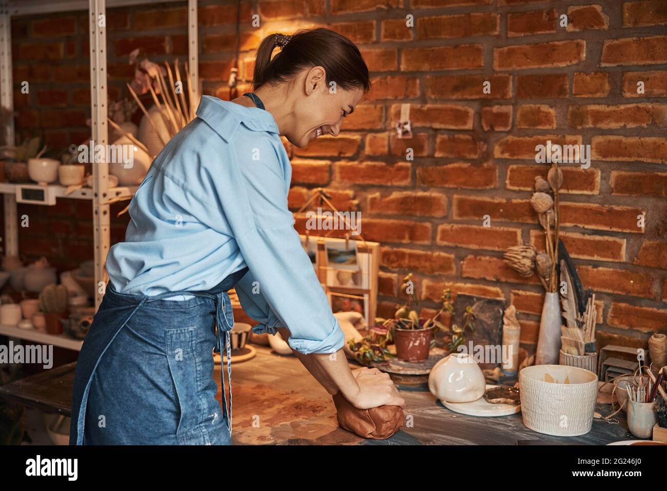 Happy positive female enjoy her handwork with clay in pottery studio ...