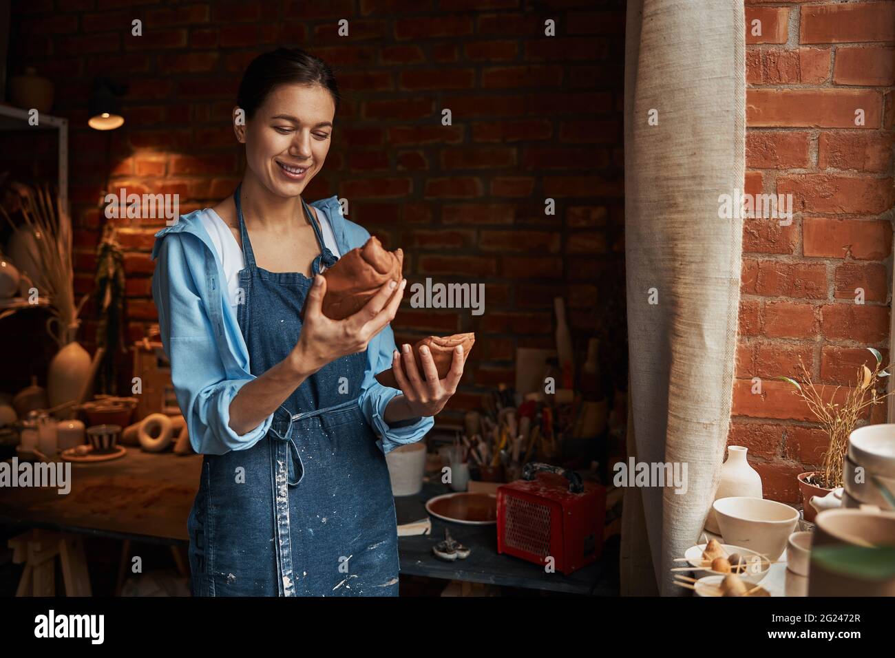 Beautiful young lady enjoy working with earthenware product in pottery ...
