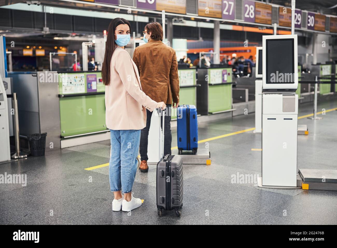 Passengers standing in line and keeping social distance at airport ...