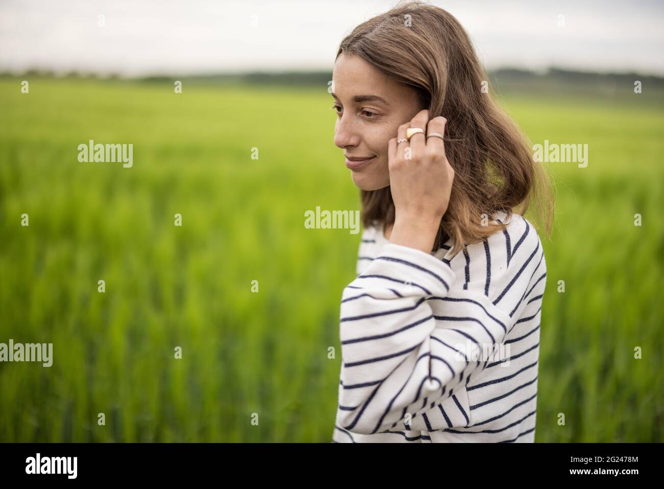 Relaxed woman standing in green field and enjoys calm nature. Freedom ...