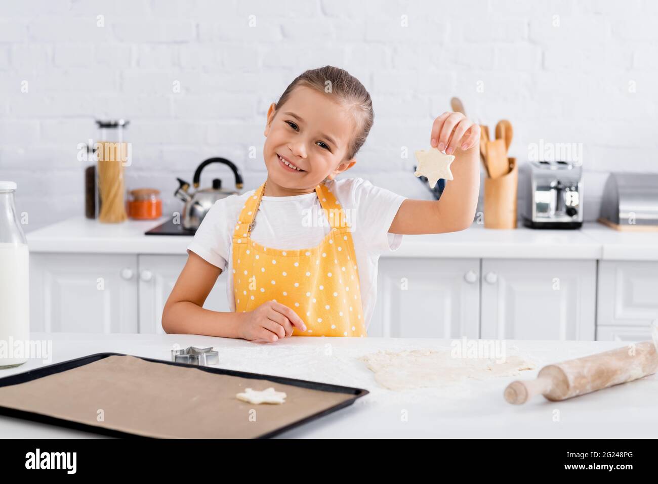 Happy girl holding dough near baking sheet and cookie cutter Stock ...