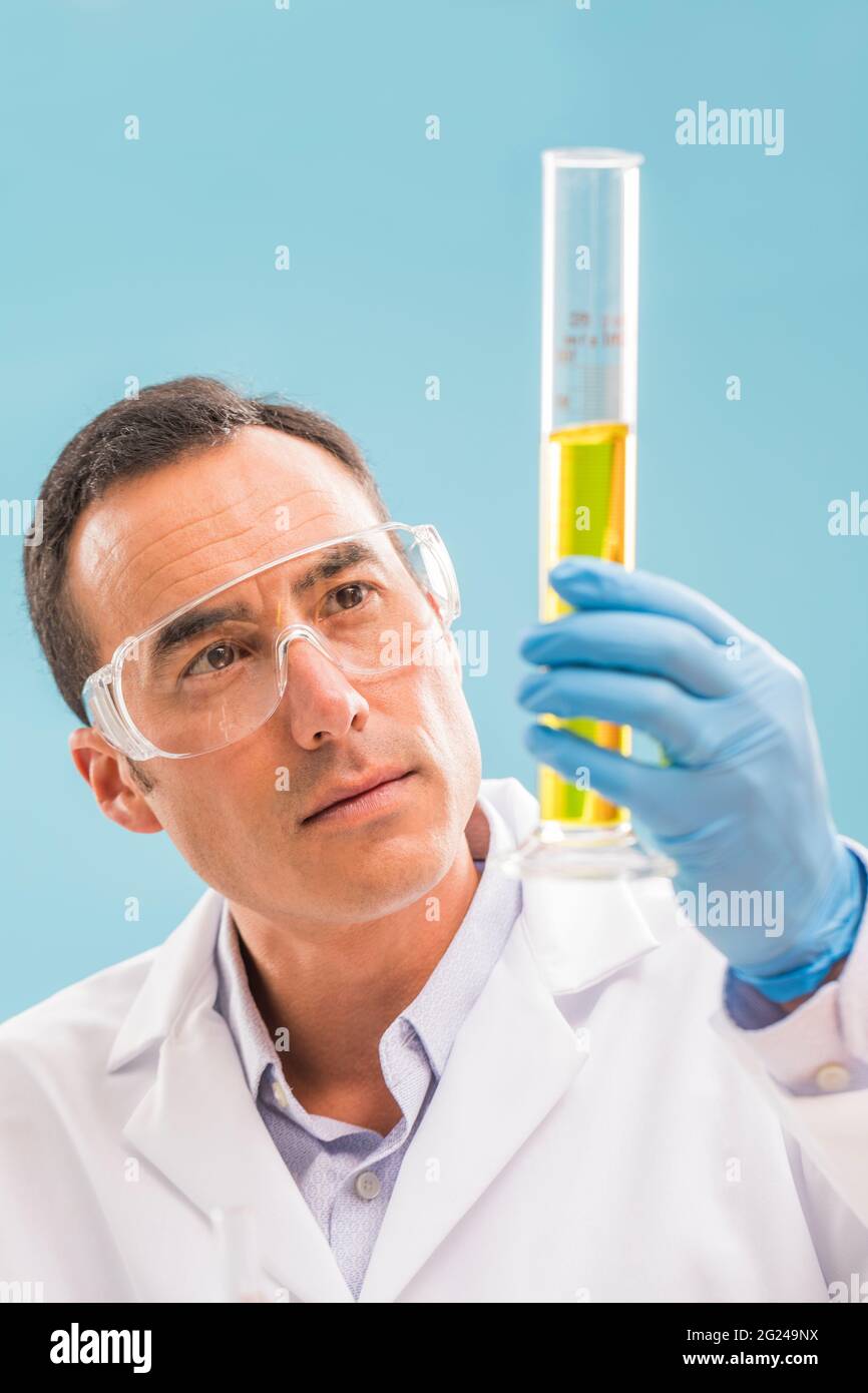 Scientist looking at yellow liquid in measuring beaker Stock Photo - Alamy