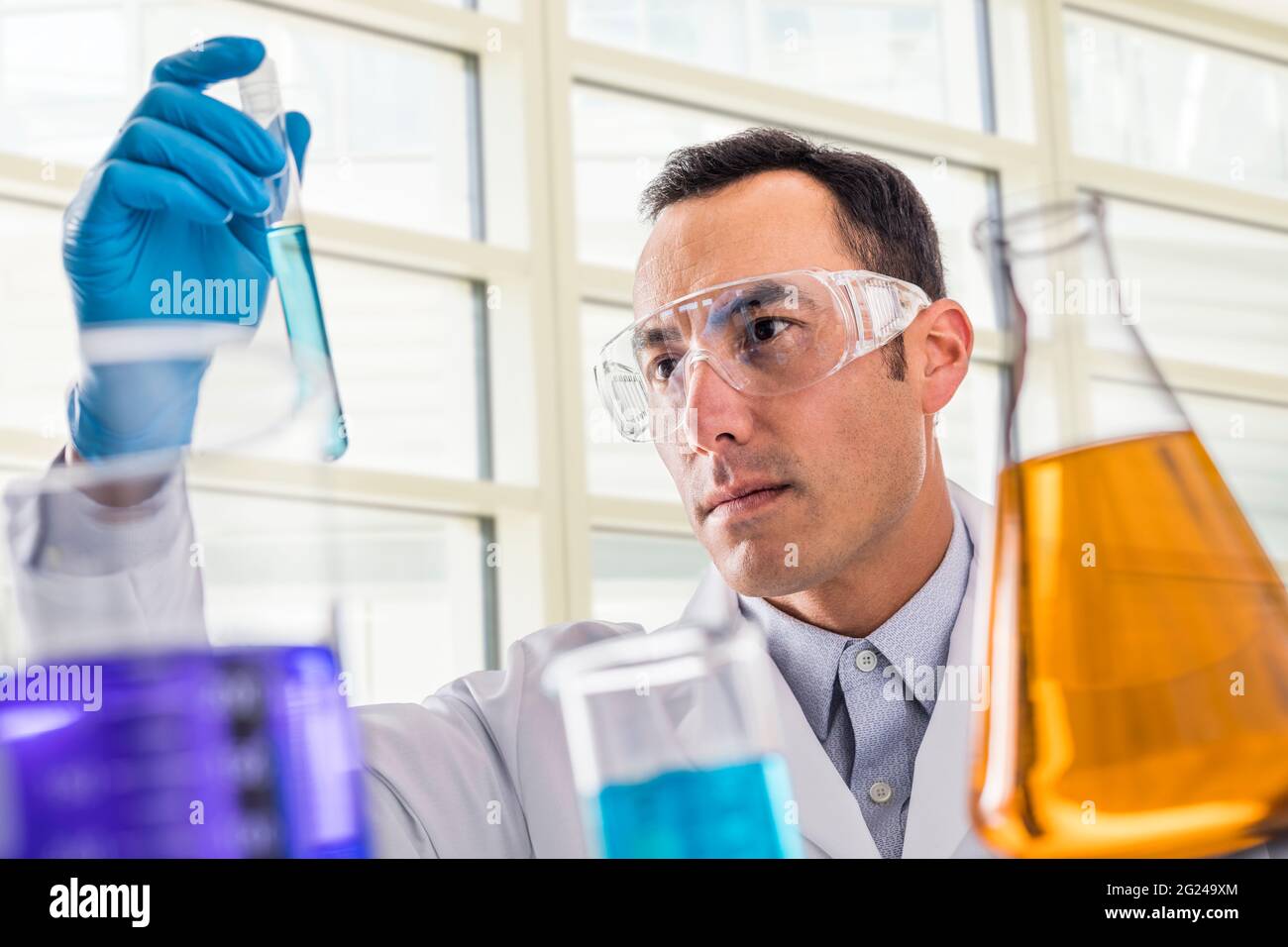 Scientist looking at blue liquid in laboratory Stock Photo - Alamy