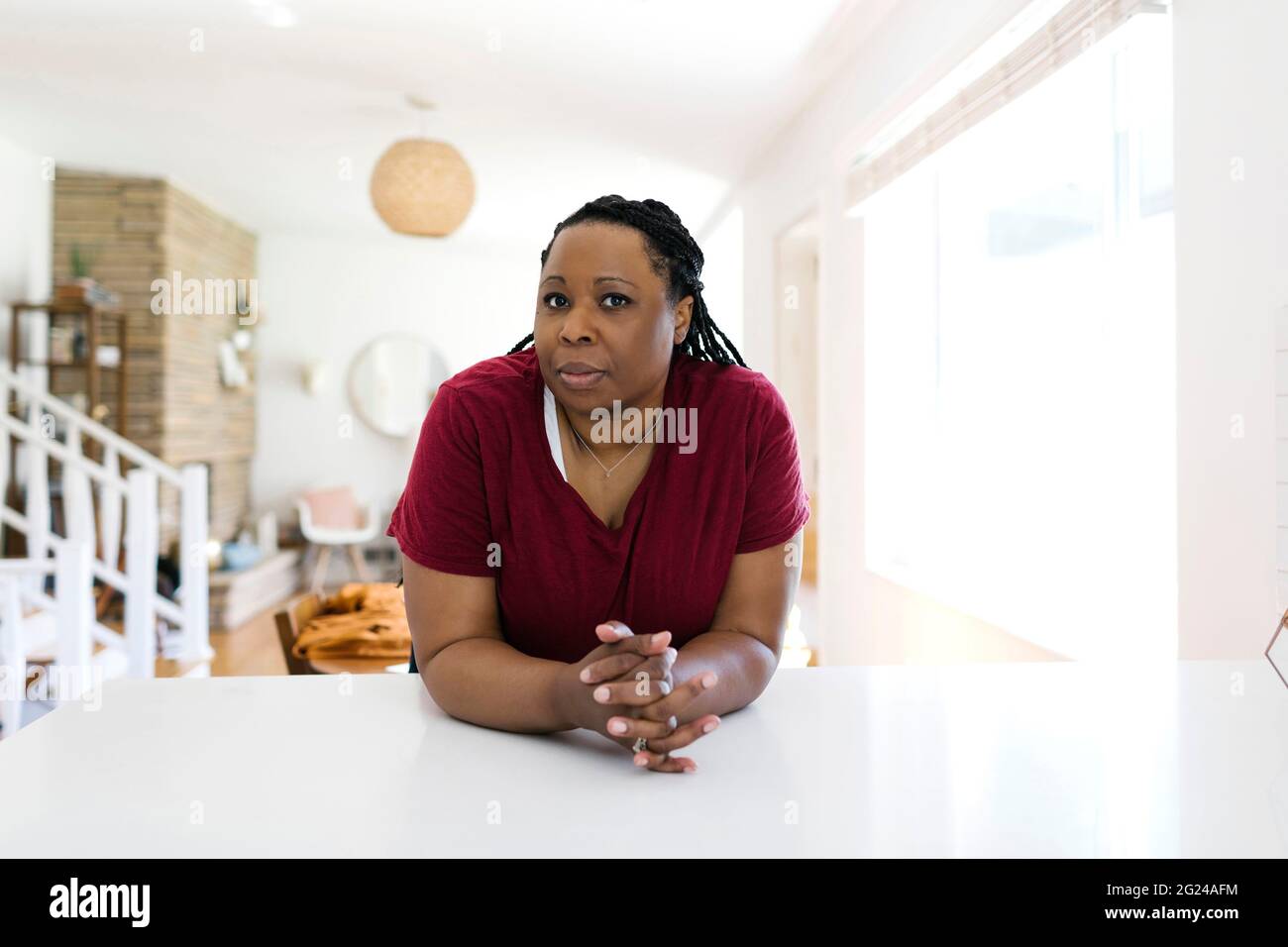 Portrait of woman leaning against kitchen counter Stock Photo - Alamy