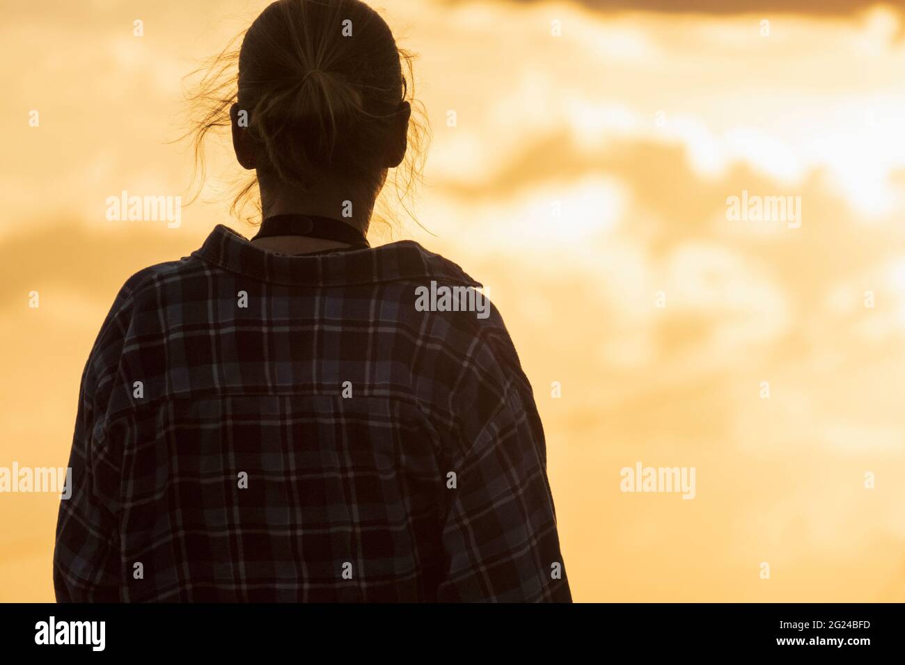 Rear view of woman standing against sunset sky Stock Photo - Alamy