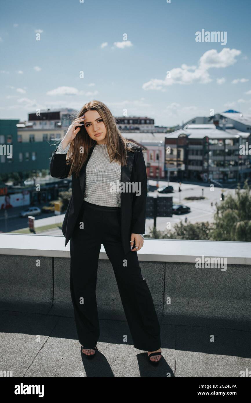 Young female with a classic outfit posing on a rooftop Stock Photo - Alamy