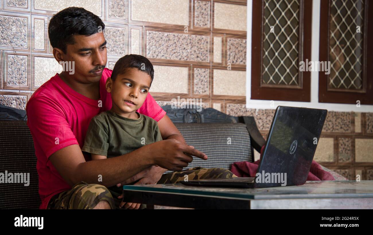 Man and cute child using laptop. Working Indian father works from home ...