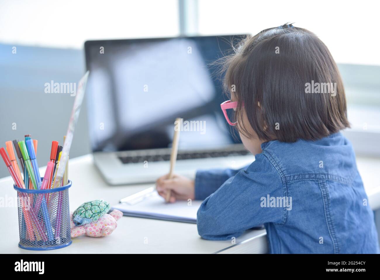 Girl sitting at a desk doing her homework Stock Photo - Alamy