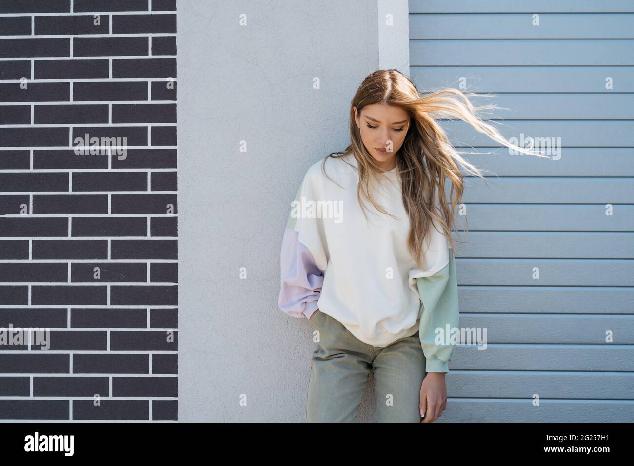 Beautiful windswept woman standing outdoors leaning against a wall ...