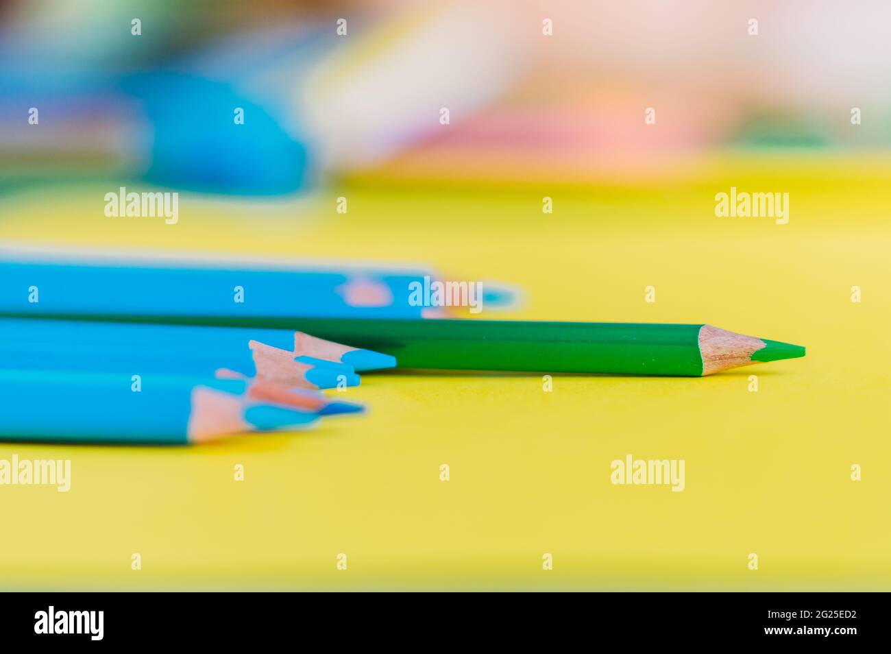 Sharpened blue pencils andone green pensil on a yellow background Stock ...