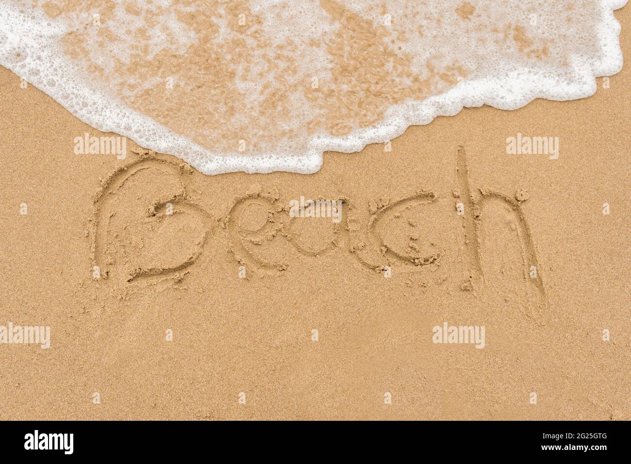 Word BEACH handwritten on the sand of beach Stock Photo - Alamy