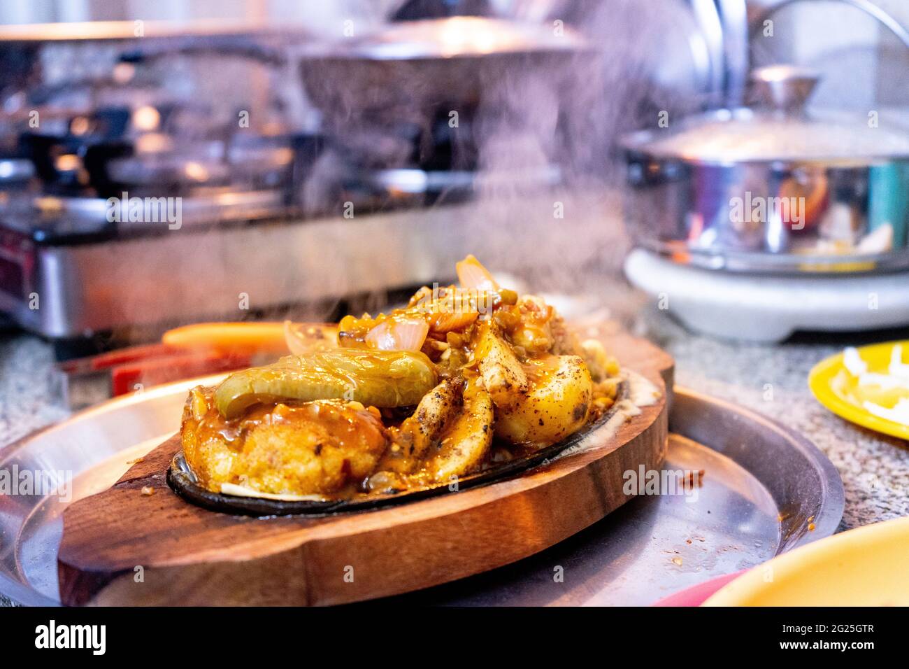 Indian asian sizzler dish served on a wooden tray with an iron hot ...