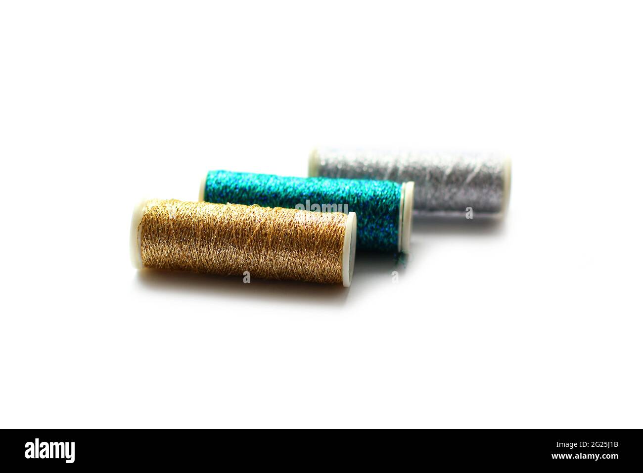 Sewing threads on a white background. Bright shiny threads. Gold and ...