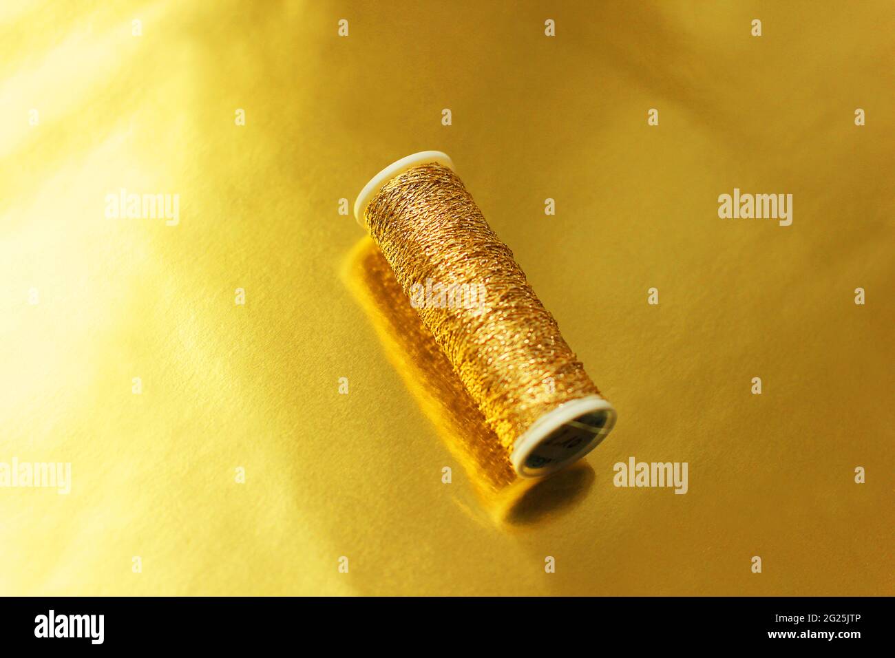 Sewing gold threads on a gold background. Bright shiny threads ...