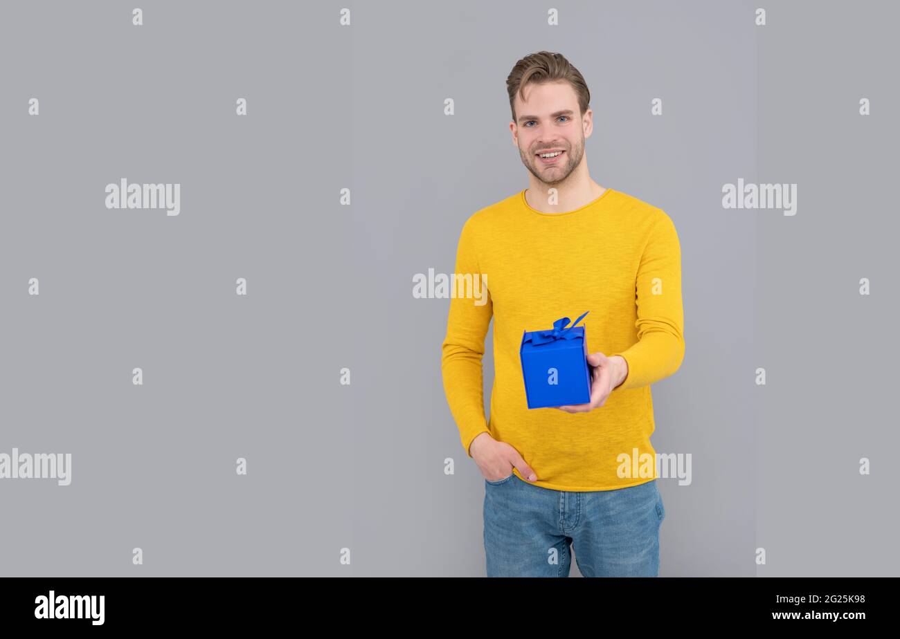 Happy handsome guy give present box grey background copy space, giving ...
