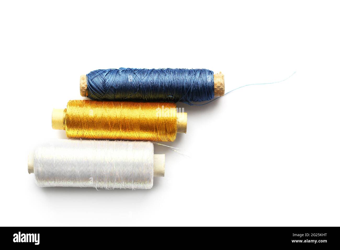 Sewing threads on a white background. Bright shiny threads. Gold and ...