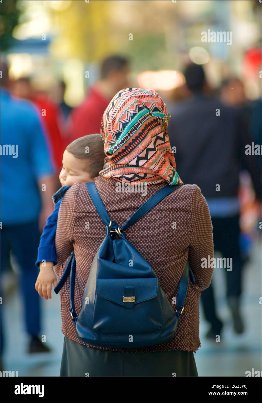 Turkish woman with headcloth carrying a sleeping toddler. Istanbul ...