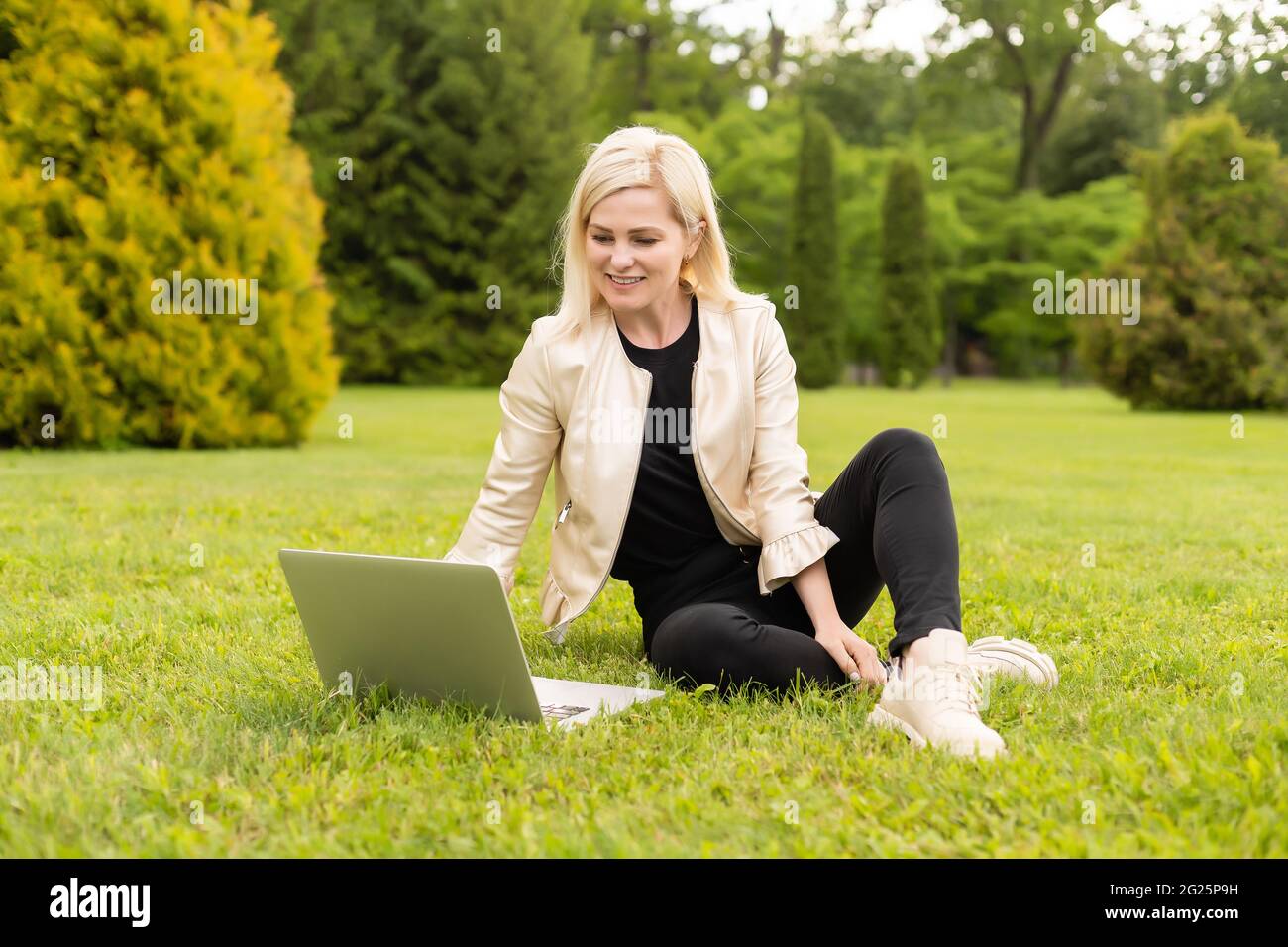 Female copywriter working on laptop in the park, view over the shoulder ...