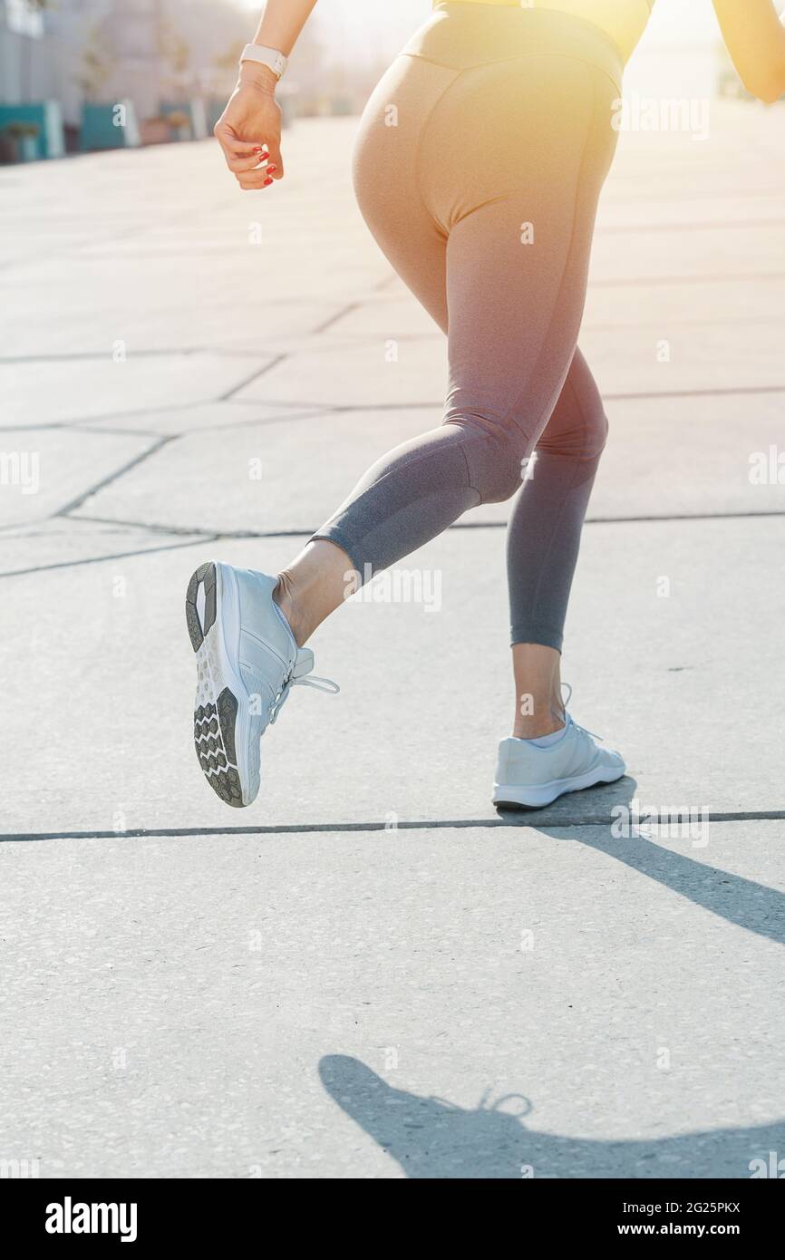 Running woman on the pavement outdoors. Cropped, lower part of a body ...