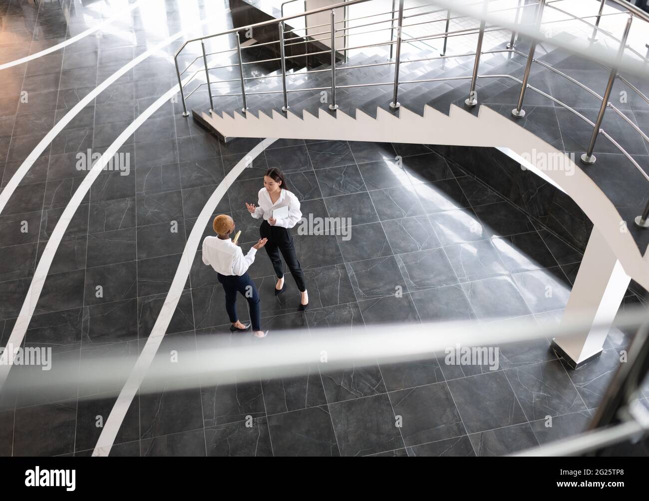 Diverse colleagues having conversation near staircase Stock Photo - Alamy