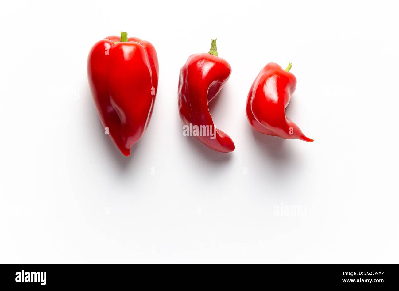 Three red peppers in a white background Stock Photo - Alamy