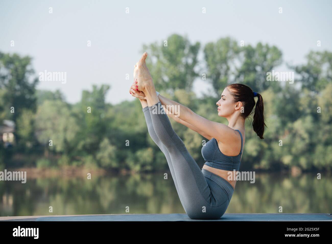 Side view of young woman doing yoga outdoors in a beautiful spot on a ...