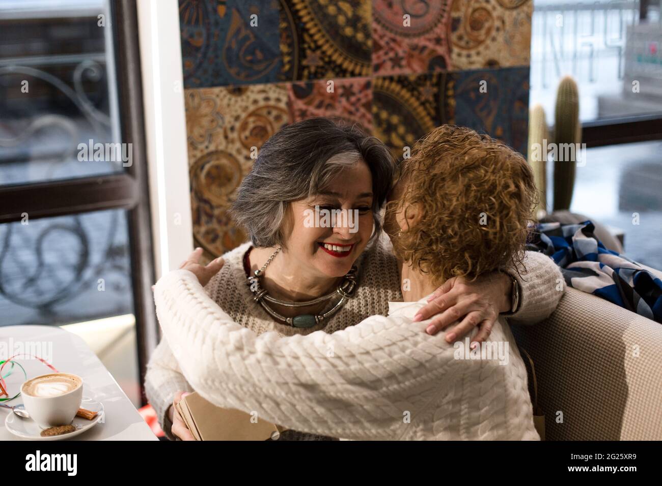 Two adult women thank each other, hug and laugh Stock Photo - Alamy