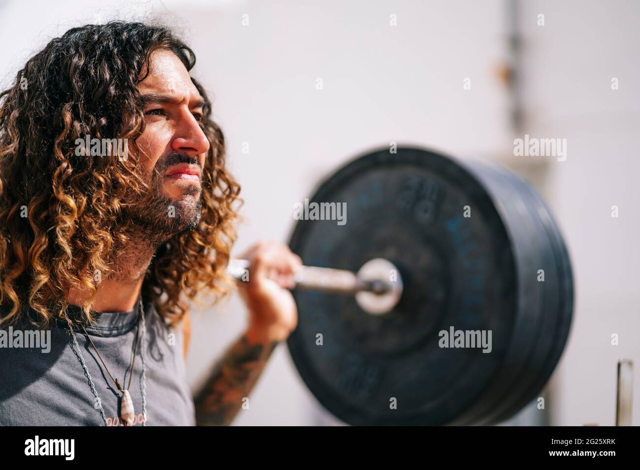 Long haired man with suffering face holding dumbbells Stock Photo - Alamy