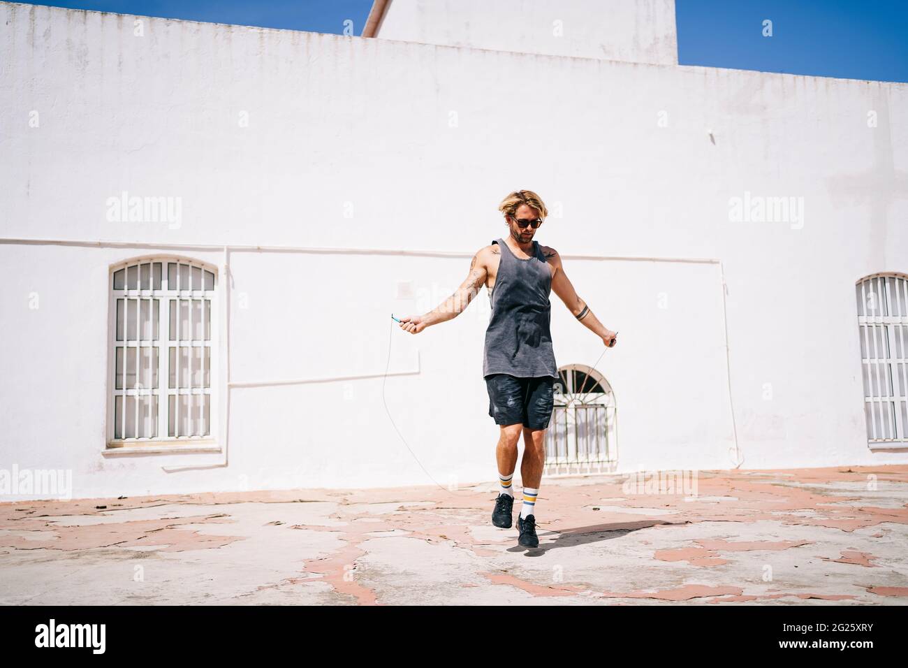 Long-haired athlete man skipping rope outdoors Stock Photo - Alamy