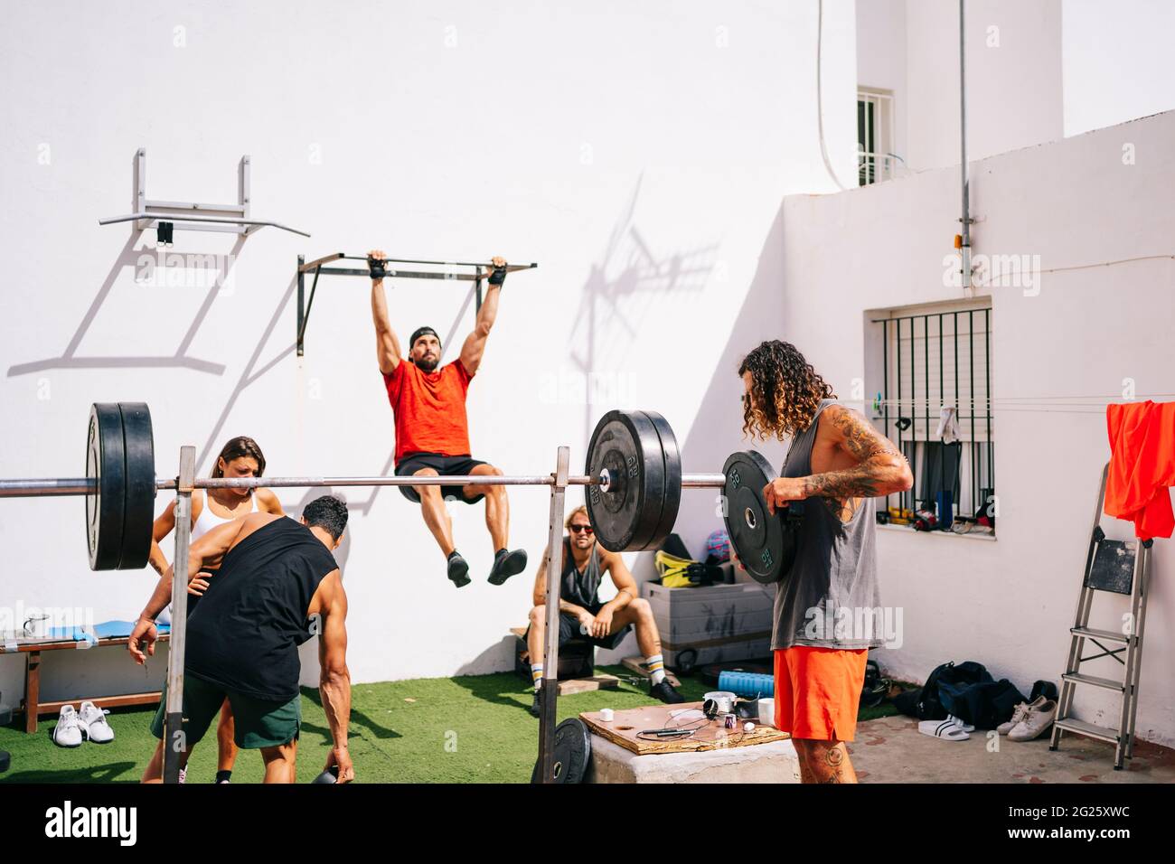A group of sporty friends perform different exercise routines outdoors ...