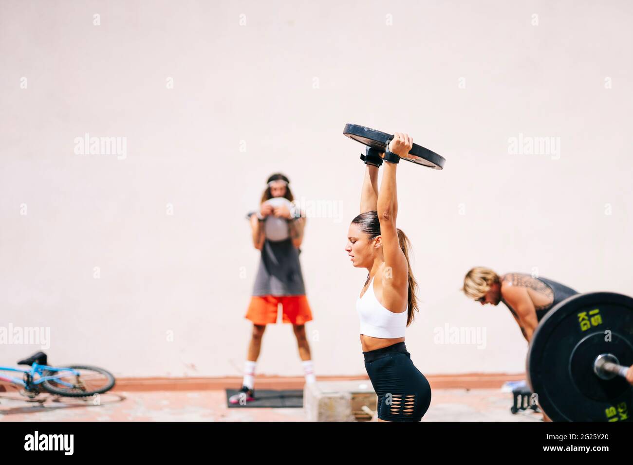 A group of sporty friends perform different exercise routines outdoors ...