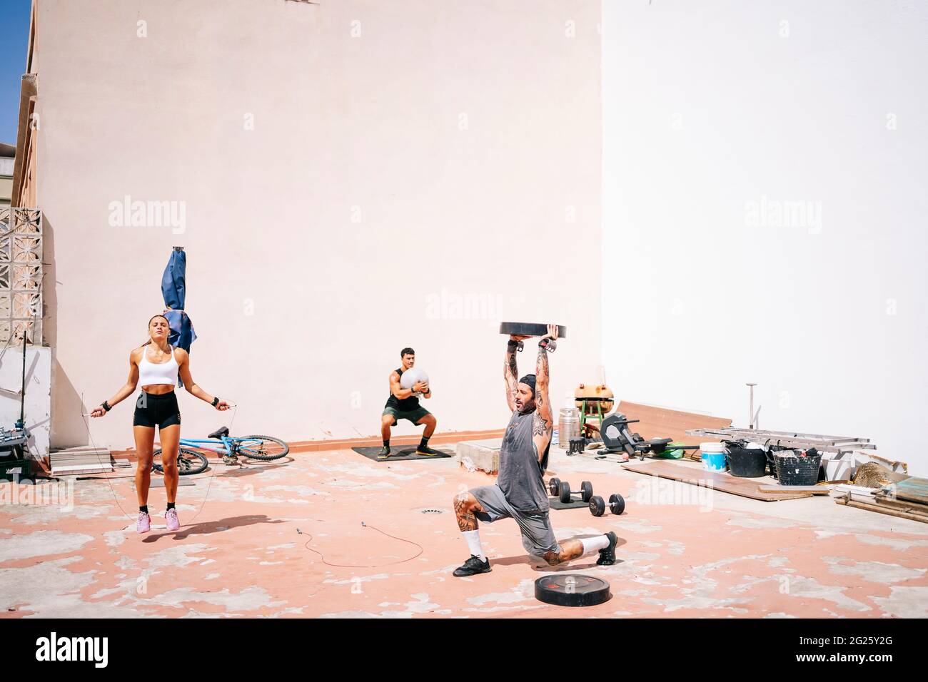 A group of sporty friends perform different exercise routines outdoors ...