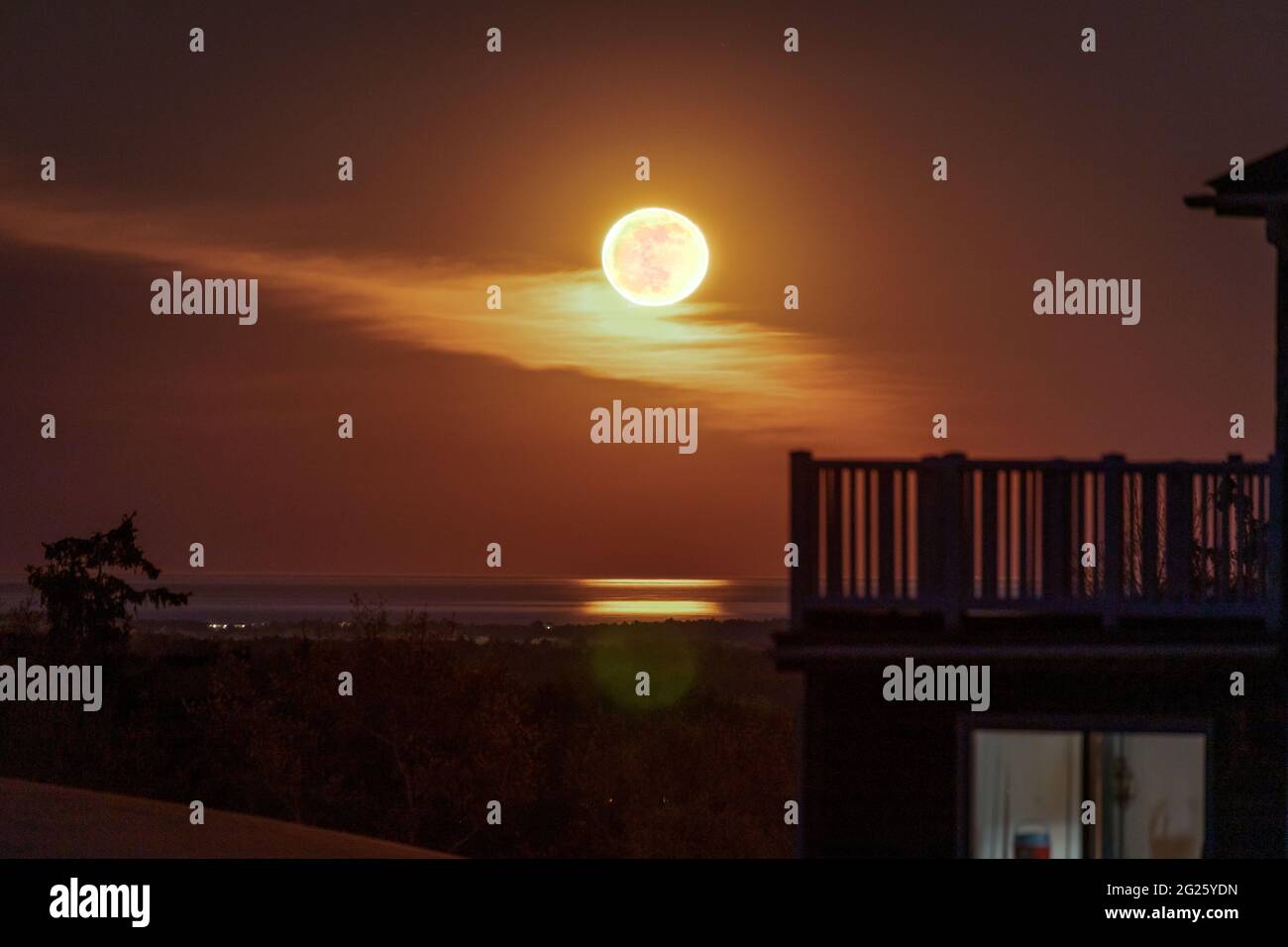 Full moon rising above beach glowing in the night sky Stock Photo - Alamy