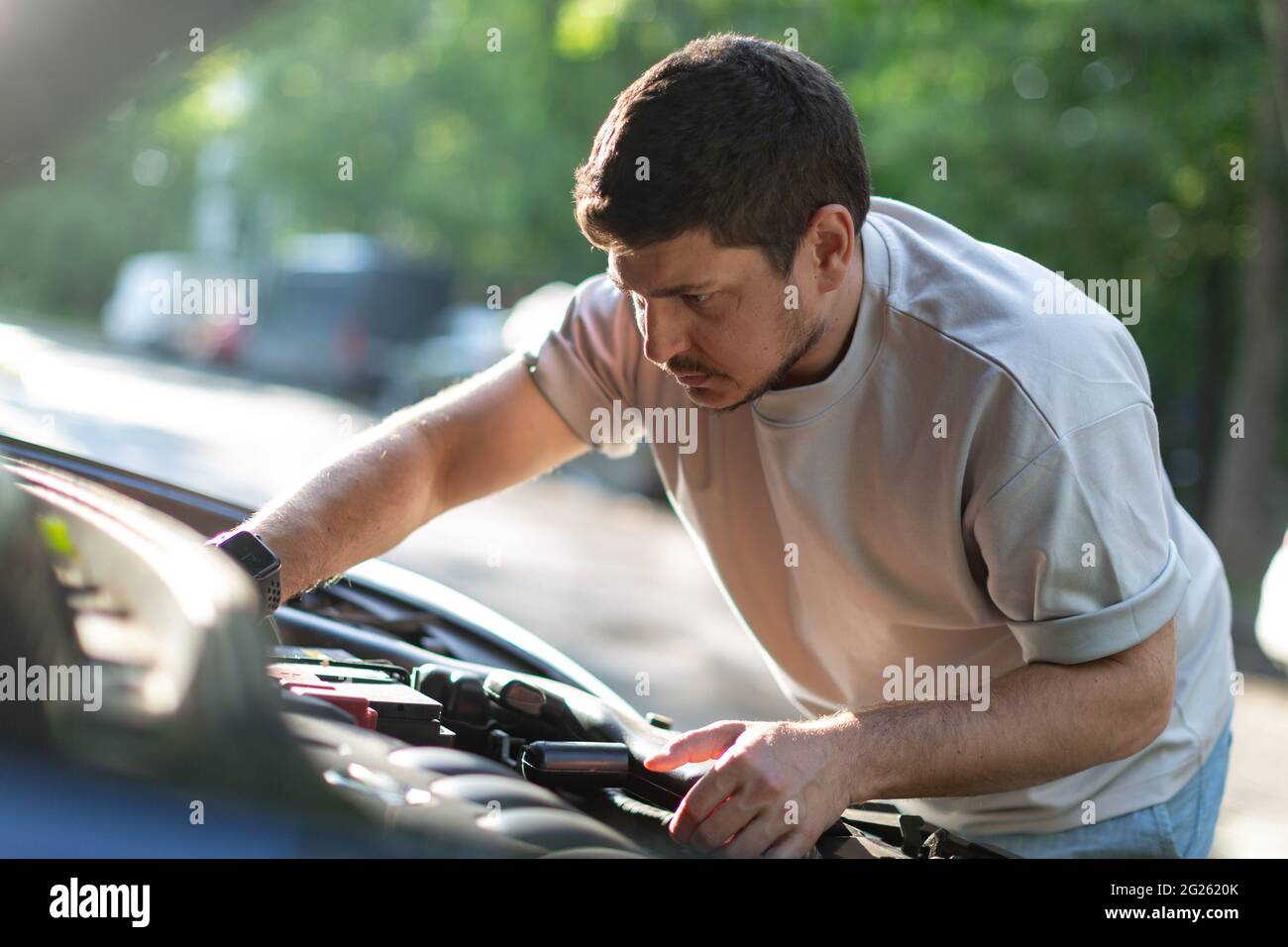 a man on a city street checks the operation of the car, looks under th ...