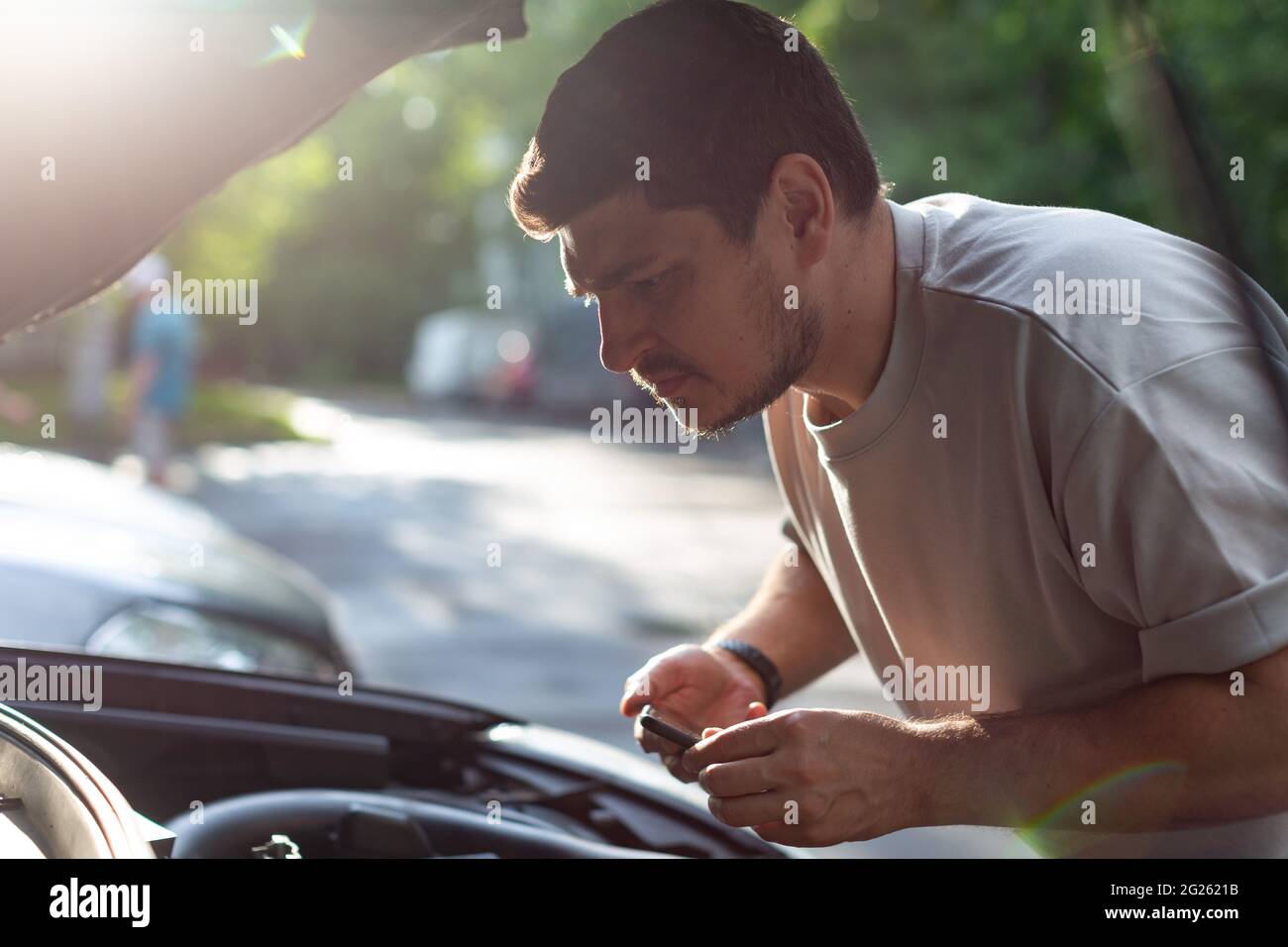 a man on a city street checks the operation of the car, looks under th ...