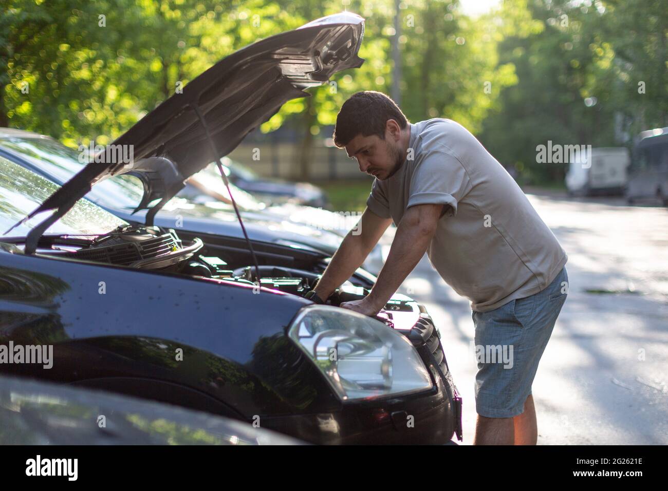 a man on a city street checks the operation of the car, looks under th ...