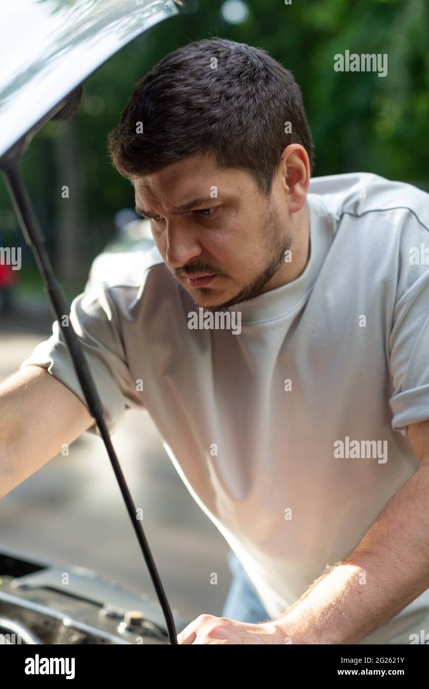 a man on a city street checks the operation of the car, looks under th ...