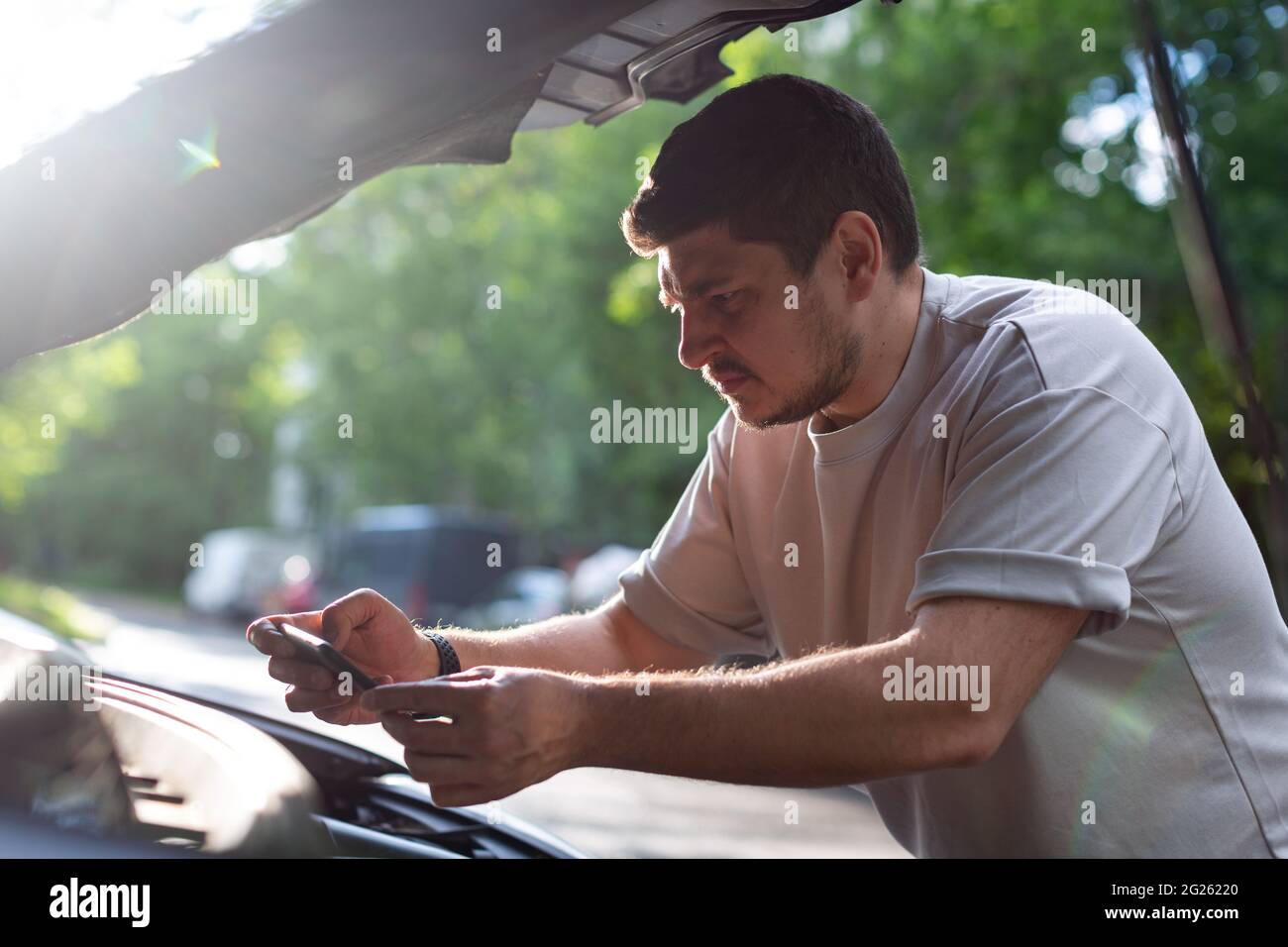 a man on a city street checks the operation of the car, looks under th ...