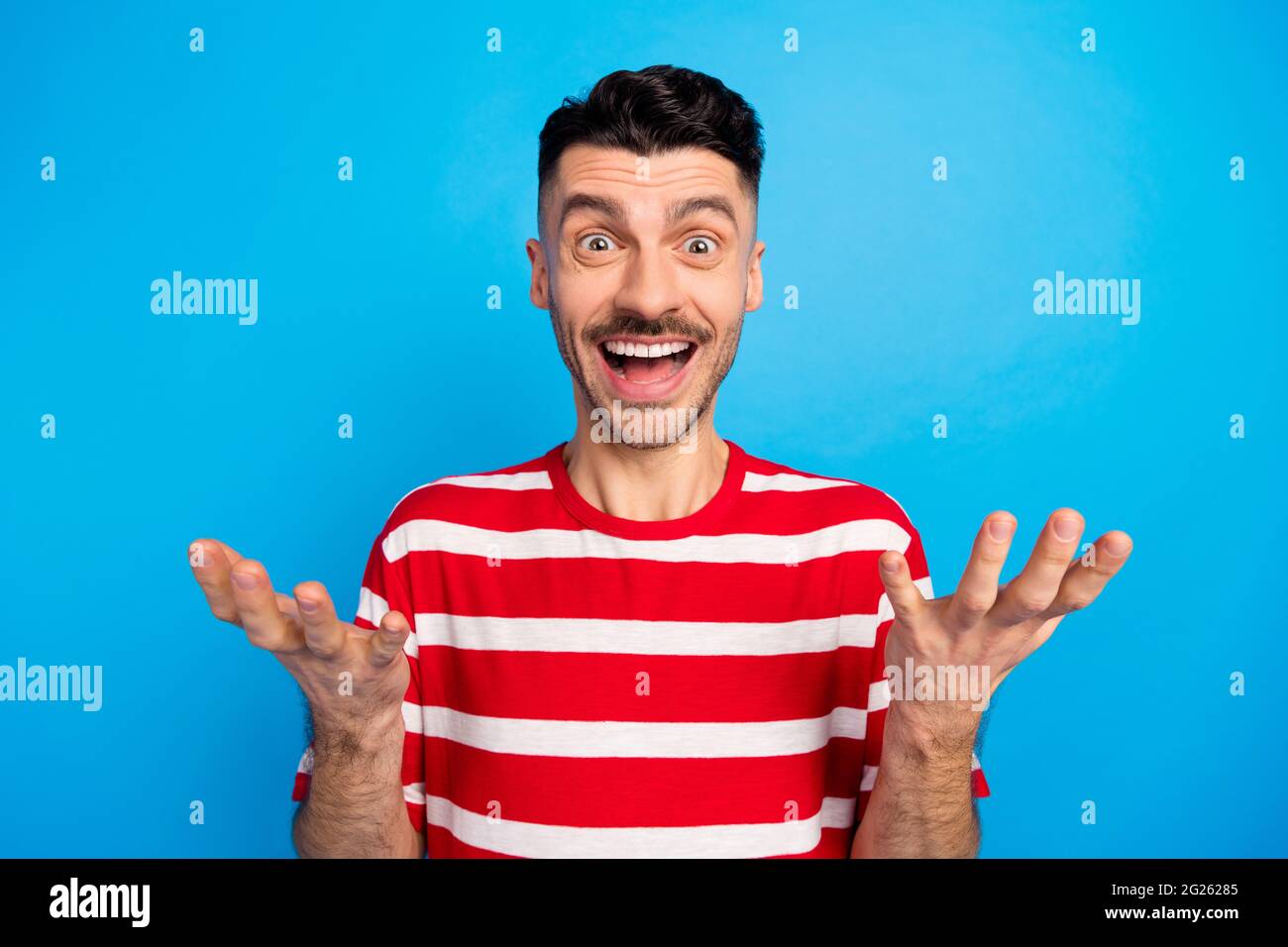 Photo of charming shocked young positive man raise hands unexpected ...