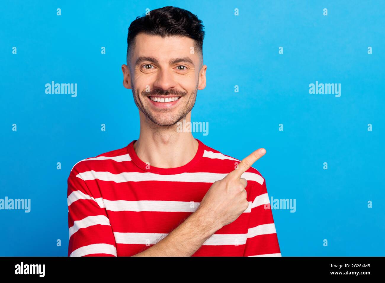 Photo of joyful cheerful young man point index finger empty space good ...