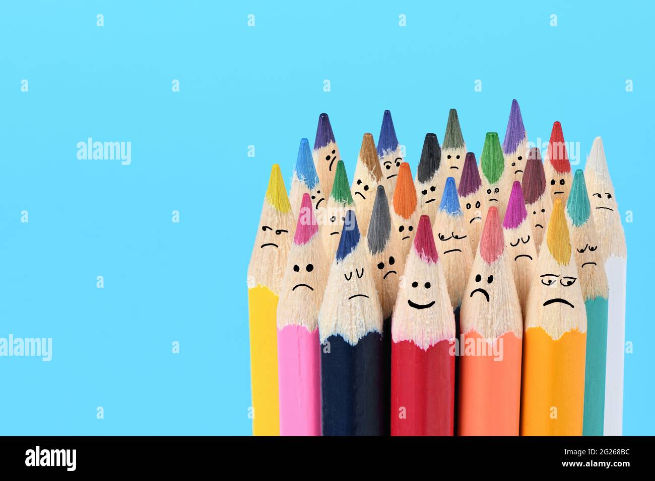 Bright smiling pencil among big set of colored sad pencils. Close up ...