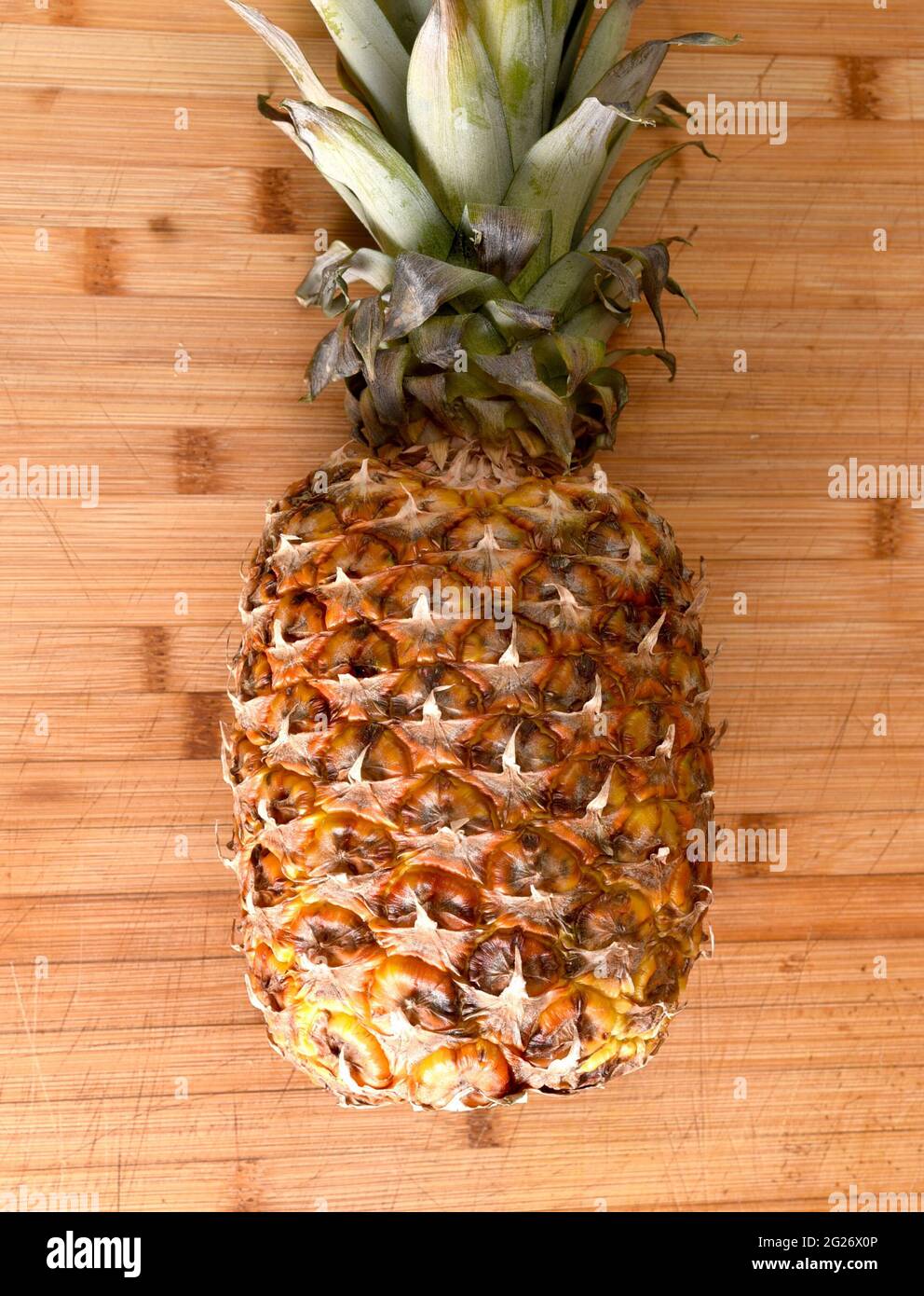 A ripe pineapple on a bamboo wood surface Stock Photo - Alamy