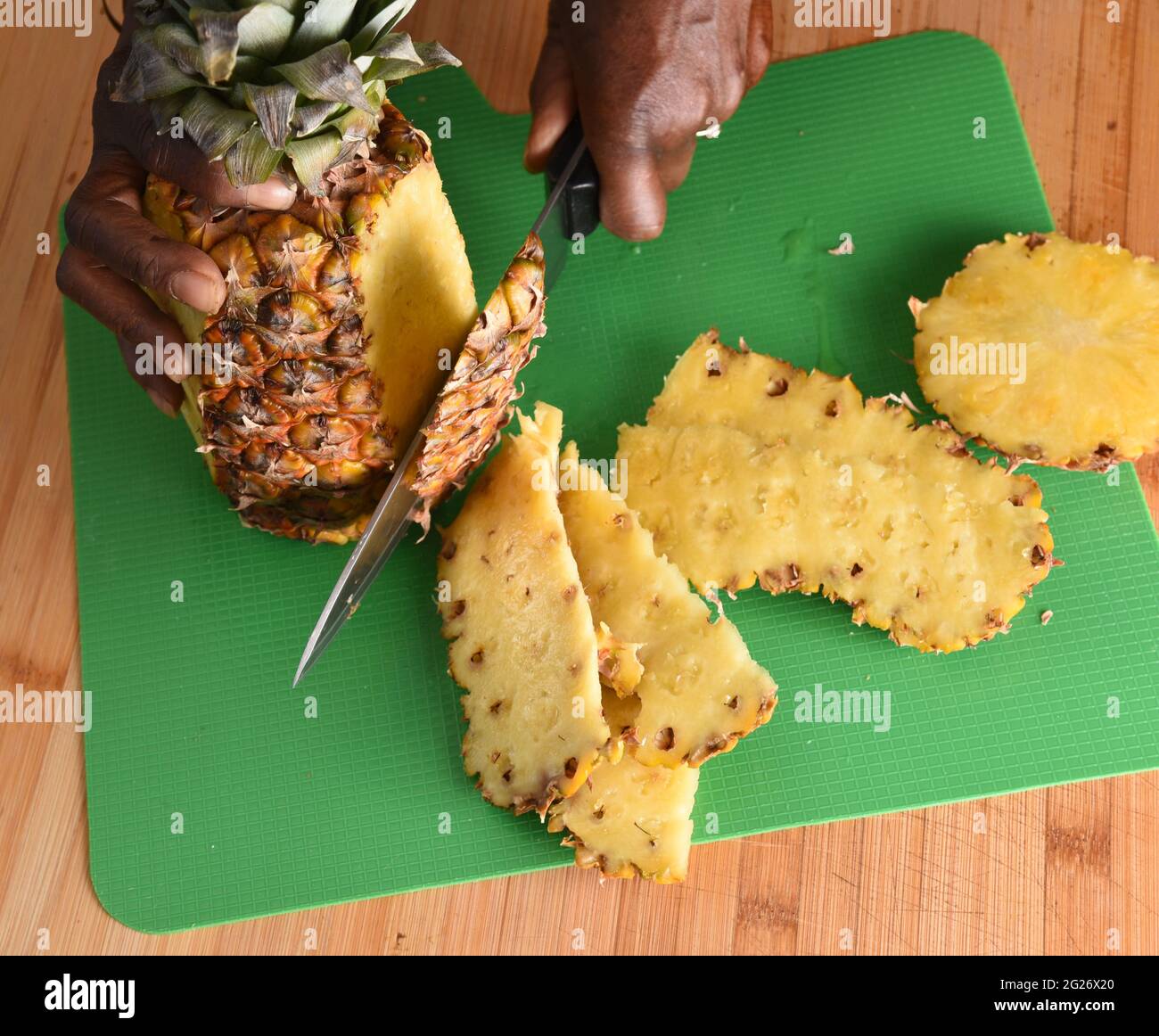 removing the skin of a pineapple with a knife on chopping board Stock ...