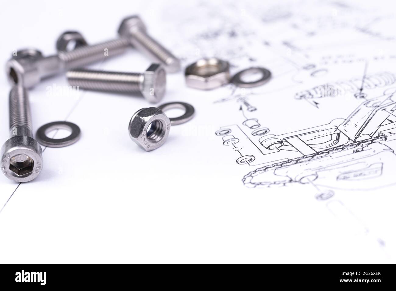 Closeup shot of various steel nuts and bolts on the blueprint plans ...