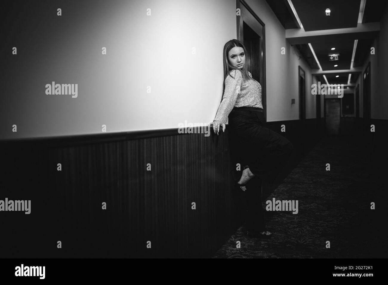 Elegant adult woman wearing a suit and leaning on a wall in a hotel ...