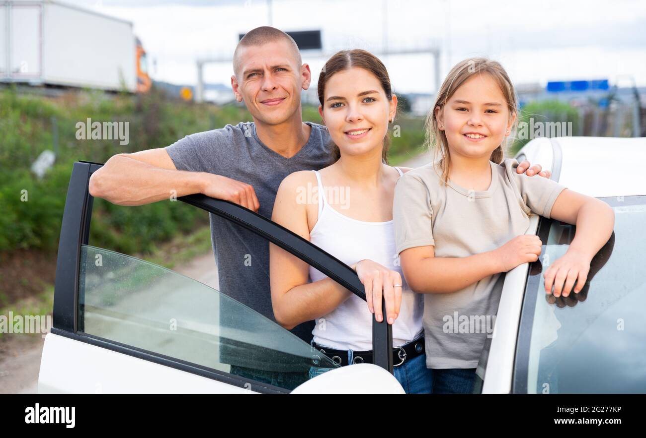 Positive family standing near an open car Stock Photo - Alamy