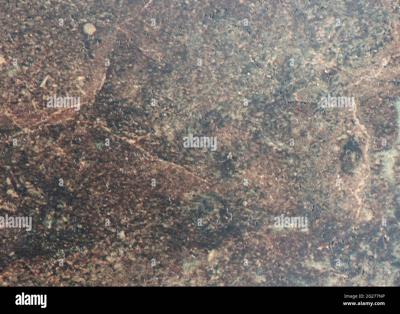 A flat surface of natural dark stone with brown blotches and small ...