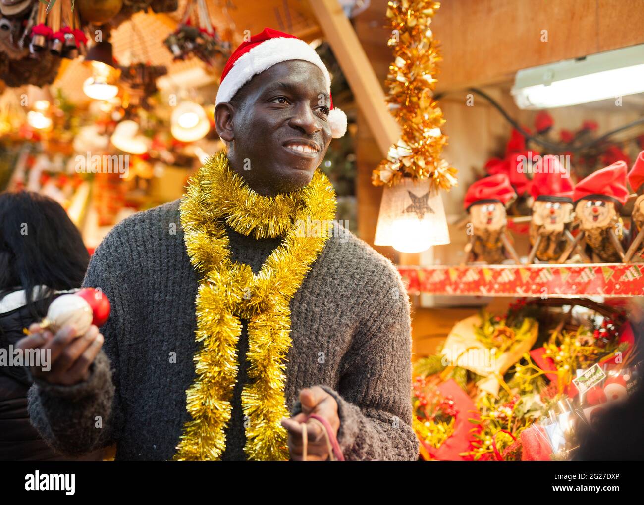 Smiling man in Santa hat selecting festive Christmas decoration Stock ...