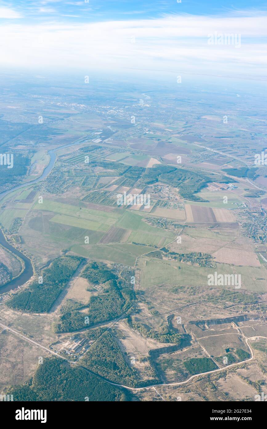 Aerial view from airplane window above green ground. View from the ...